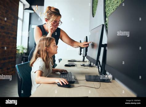 Computer Class At School Teacher Assisting Schoolgirl While Class At