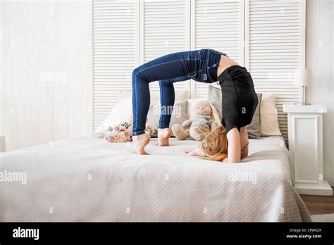 Young Girl Doing Gymnastics Over White Background Girl Makes A Gymnastic Bridge On The Bed In