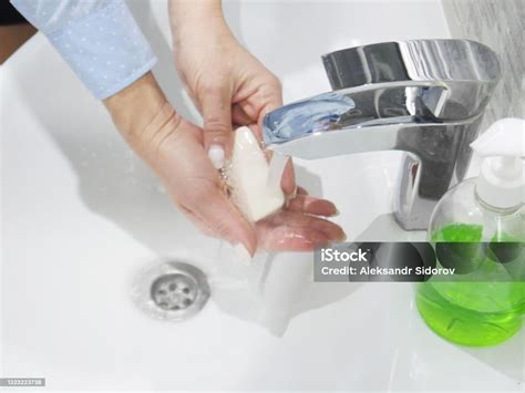 사람들은 흐르는 물에 세균을 싸우기 위해 알코올 기반 손 소독제와 항균 비누로 코로나 바이러스 질병을 죽일 비누의 막대와 싱크대에 손을 씻는다 집에 머물고 손을 씻으십시오