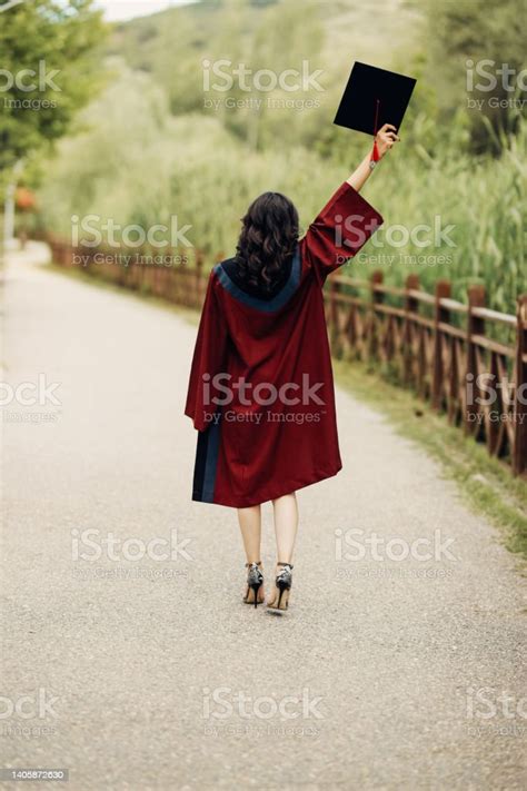 졸업 가운을 입은 젊은 여성이 녹색 공원에서 손으로 모자를 들고 있는 모습 20 24세에 대한 스톡 사진 및 기타 이미지