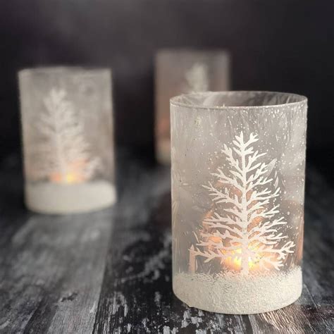 Three Frosted Glass Candle Holders With Lit Candles In The Shape Of