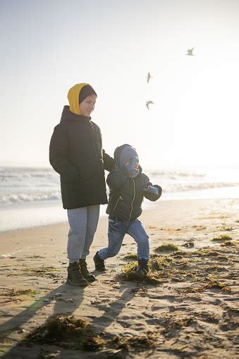 10 세와 4 세의 두 형제는 화창한 겨울 날에 해변에서 놀고 즐거운 시간을 보입니다 2명에 대한 스톡 사진 및 기타 이미지