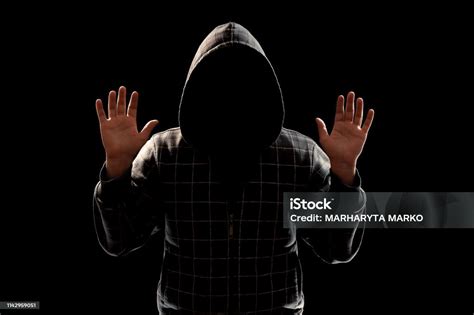 후드에 있는 남성의 실루엣 검은 배경에 얼굴이 보이지 않으며 카메라의 손바닥을 보여줍니다 범죄 시크릿 미스터리 비밀 익명성의