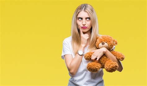 年輕美麗的金髮碧眼的女人抱著泰迪熊在孤立的背景嚴重的臉思考問題 非常混亂的想法 照片檔及更多 一個人 照片 一個人 下巴 不確定