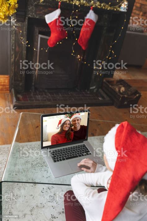 집에서 노트북에 산타 모자에 가족과 화상 통화를 가지고 산타 모자에 여자의 후면 보기 18 19세에 대한 스톡 사진 및 기타 이미지 18 19세 20 24세 3 명