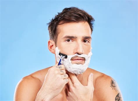 Barbear de retrato e navalha um modelo de homem se preparando no estúdio em um fundo azul