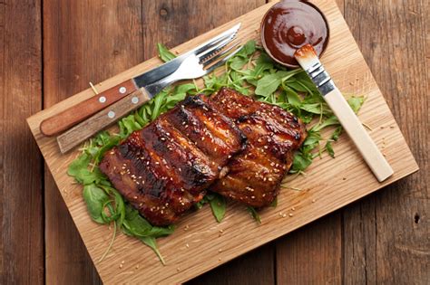 돼지 갈비 바베 큐 소스 구이 Arugula의 침대에 꿀에 Caramelized 오래 된 나무 배경에 제출 나무 보드에 맥주에