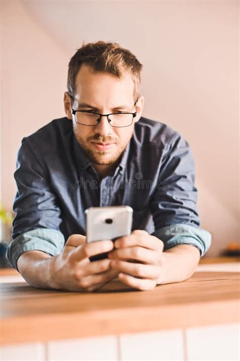 Nerd Guy With Glasses In Stylish Kitchen Follows A Recipe On The Phone Prepares Chicken Stock