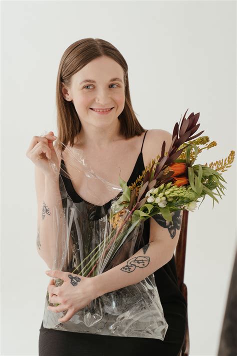 Woman In Black And White Floral Dress Holding Red And Green Flower