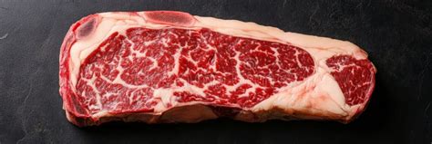 Raw Well Marbled Ribeye Steak With Fat On A Black Background Prepared