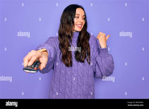 Young Beautiful Woman Using Television Remote Control Over Isolated