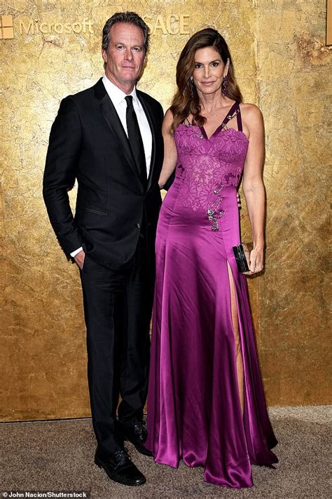 Cindy Crawford Flaunts Her Toned Legs Through A Slit In Her Silky Purple Gown As She Snuggles Up