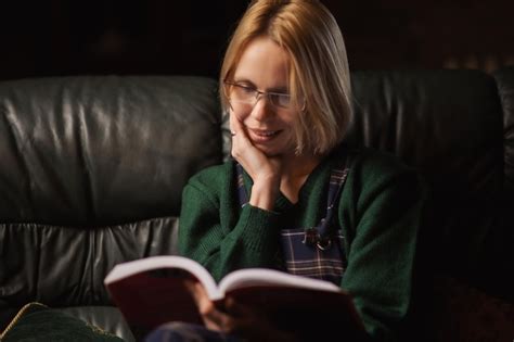 Une Femme Avec Des Lunettes Lit Un Livre Sur Le Canapé à La Maison Une