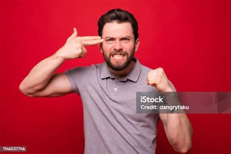 젊은 남자 촬영 및 머리에 손과 손가락을 가리키는 자신을 죽이고 고립 된 빨간색 배경 위에 자살 제스처 가리키기에 대한 스톡 사진 및 기타 이미지 Istock