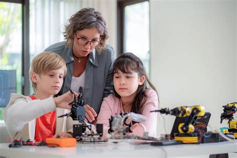 전담 과학 교사가 첨단 Stem 교실에서 로봇 팔을 제어하는 코딩을 배우도록 학생들을 안내합니다 회로 기판 컴퓨터 및 Ai 기반 기술에 둘러싸여 학생들은 창의성 문제 해결