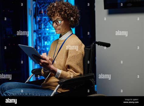 female it engineer typing information on digital tablet sitting in wheelchair she working in