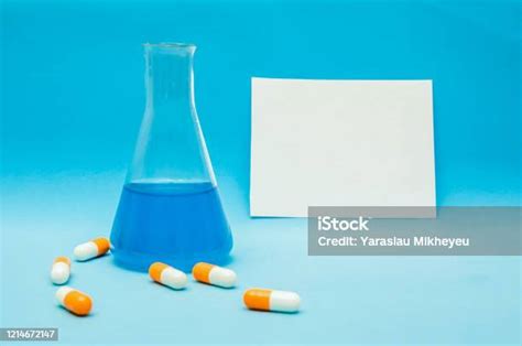파란색 배경에 파란색 액체 주황색 흰색 캡슐이있는 플라스크 배경에는 복사 공간을위한 흰색 종이 0명에 대한 스톡 사진 및 기타 이미지 Istock