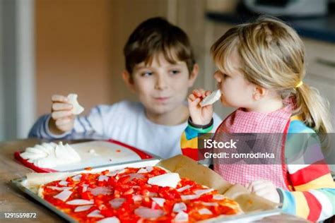 두 형제 집에서 이탈리아 피자를 만드는 어린 아이들 귀여운 유아 소녀와 학교 소년은 실내 홈 키친에서 재미를 형제 자매 가족이 식사를 돕고 준비합니다 2명에 대한 스톡 사진