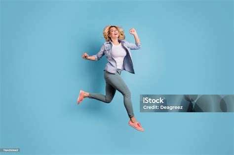 파란색 배경 위에 고립 된 바지바지를 입고 웃는 팔을 올리는 사랑스러운 매력적인 사람의 전체 길이 사진 여자에 대한 스톡 사진