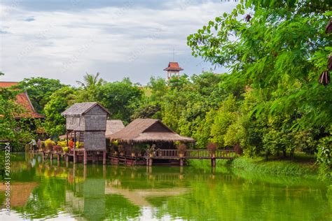 A Traditional Wooden Khmer House On Stilts Reflected By The Water Of