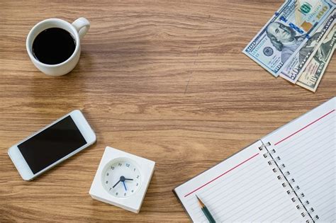 크리에이 티브 플랫 달러 현금 지폐 노트북 클립보드 스마트폰 시계 커피 나무 테이블에 연필 비즈니스 재무 계획 및 저장 개념의