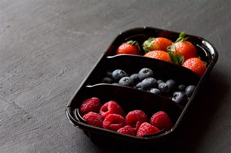 신선한 달콤한 딸기 딸기 블루 베리와 라즈베리트레이에 거짓말 검은 배경에 상자 수확 개념 검은 색 배경에 열매를 섞는다 텍스트에 대한 복사 공간이 있는 과일 건강한 식생활에