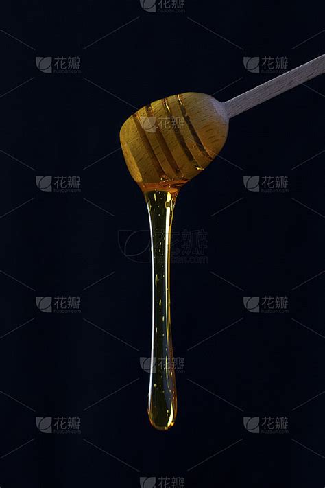 浓稠的金色蜂蜜从木勺中滴落在黑色背景上