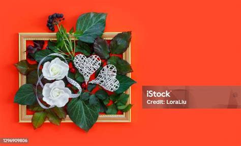 발렌타인 데이를 위한 밝은 오렌지 벽에 빈티지 나무 프레임에 녹색 단풍과 하트가 있는 아름다운 흰색 장미 창조적 인 인사말 카드 0명에 대한 스톡 사진 및 기타 이미지