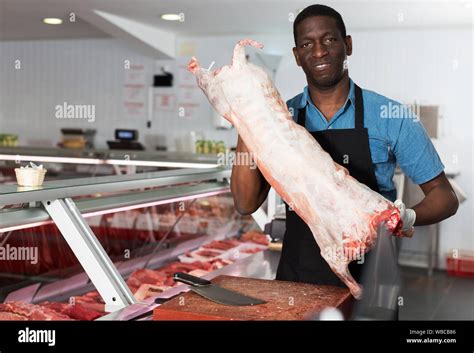 African American Adult Butcher Processing Carcase Of Young Lamb For