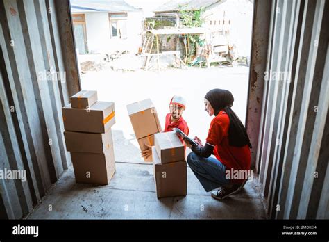 Male Workers In Red Lifting Boxes With Female Workers Checking Stock Photo Alamy
