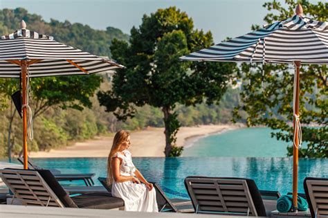 수영장 근처의 일광욕 용 의자에 앉아있는 흰색 드레스와 모자를 쓴 여행자 여성 30 34세에 대한 스톡 사진 및 기타 이미지 30 34세 고급 호텔 관광 Istock