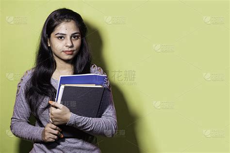 微笑的印度女学生拿着书籍和档案，学院或学校的学生和教育理念与拷贝空间。