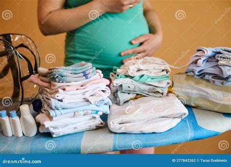 Close Up Of Pile Of Clean Ironed Newborn Clothes And Bottles With