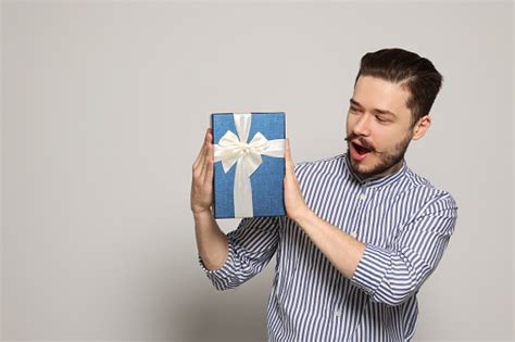 밝은 회색 배경에 선물을 가진 감정적인 남자 텍스트를 위한 공간 20 24세에 대한 스톡 사진 및 기타 이미지 20 24세 감정 공휴일 Istock