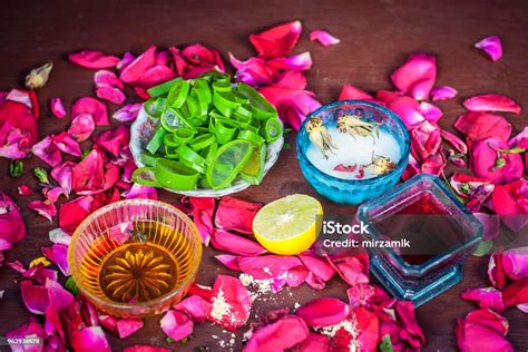 알로에 베라 젤 벌 꿀 우유 크림 레몬의 구성 된 허브 얼굴 팩 닫고 장미와 장미 물과 장미 꽃잎 어두운 고딕 색상에서 나무 표면에 얼굴 팩이 무딘 피부를 제거합니다 0명에