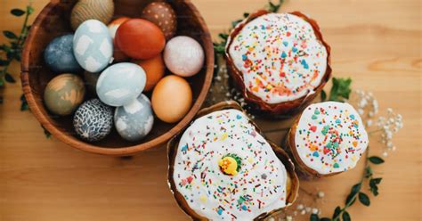 수제 부활절 케이크와 세련된 부활절 달걀은 꽃이 있는 소박한 테이블에 나무 그릇에 자연스럽게 염색되었습니다 행복한 부활절 전통적인 부활절 빵 플랫 레이 사진