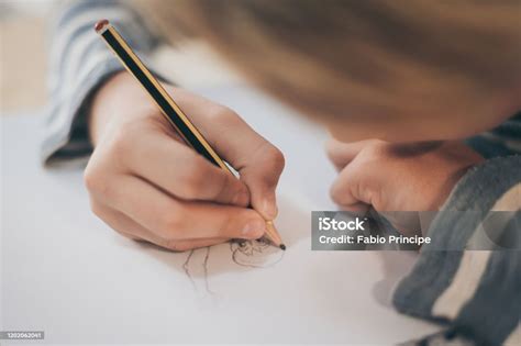 연필로 학생 그림의 보기를 닫습니다 종이에 숙제를 쓰는 소년 아이는 연필을 들고 집에서 만화를 그립니다 테이블에 앉아 십대 그리기입니다 교육 예술 인재 능력 개념 공부에