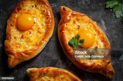 치즈로 속을 채우고 달걀 노른자를 얹은 Ajarian Khachapuri 어두운 배경에 전통적인 조지아 Khachapuri