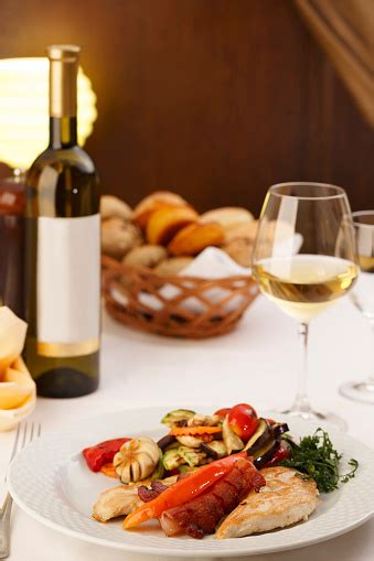 치킨 베이컨 구운된 야채와 접시 와인 병 및 배경에서 와인 글라스에 배열 우아한 부드러운 빛으로 선택적 포커스 설정에서 전통 요리 0명에 대한 스톡 사진 및 기타 이미지