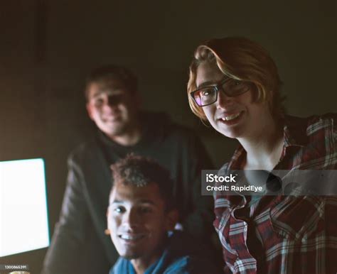 Group Of Young Computer Nerds Gathered Around A Glowing Screen At Night