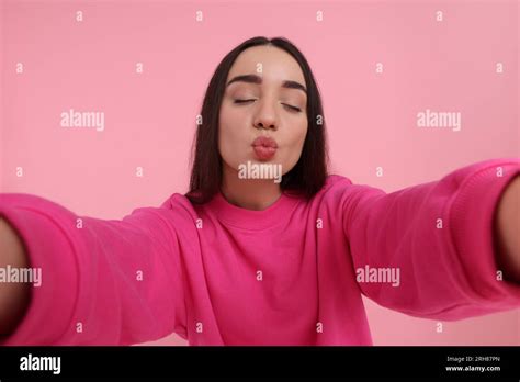 Young Woman Taking Selfie And Blowing Kiss On Pink Background Stock