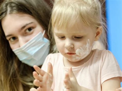 Portrait Of Adorable Little Blonde Girl With Cream On Her Face Copying