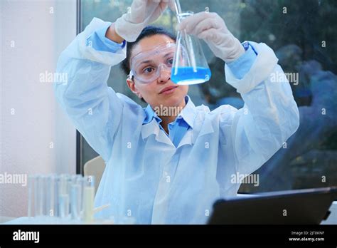 Multi Ethnic Woman Mixing The Blue Solution In Flat Bottomed Flask Conducting Chemical