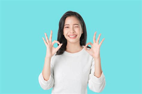초상화 행복 아시아 여자는 파란색 배경에 카메라를보고 확인 기호와 미소 마녀를 보여줍니다 쾌활한 소녀 제스처 스튜디오 아시아에