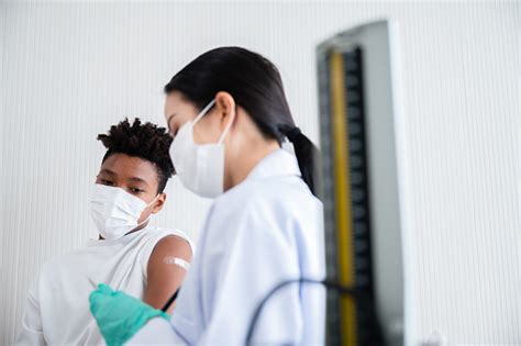 아프리카 남자는 상처를 커버하고 예방 접종 후 주사기를 들고 여성 의사 또는 간호사를보고 석고와 함께 쇼를 앉아 코로나바이러스