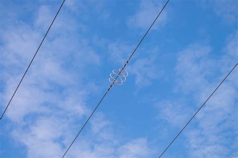 Premium Photo High Voltage Wires With A Spiral Coil Against The Blue Sky Twisted Wire With