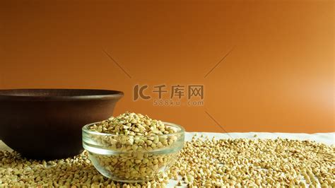 棕色背景上透明玻璃碗中的绿色荞麦。高清摄影大图 千库网
