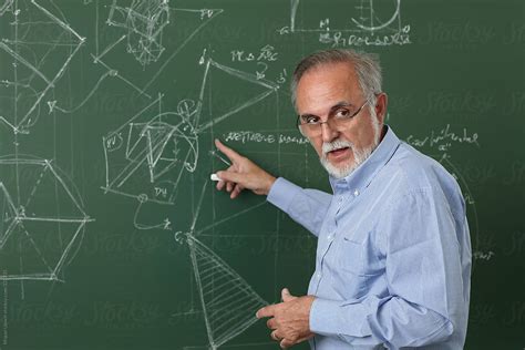 Senior Professor Teaching In Front Of The Blackboard By Stocksy