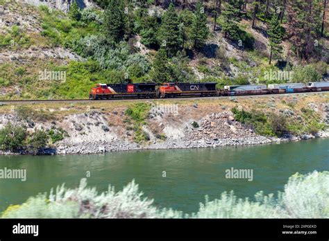 Cargo Train With Locomotive On Railroad Track By Fraser River Of The