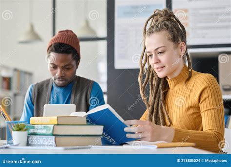 Menina Lendo Livro Enquanto Sentada Na Biblioteca Foto De Stock Imagem De Adulto Classe
